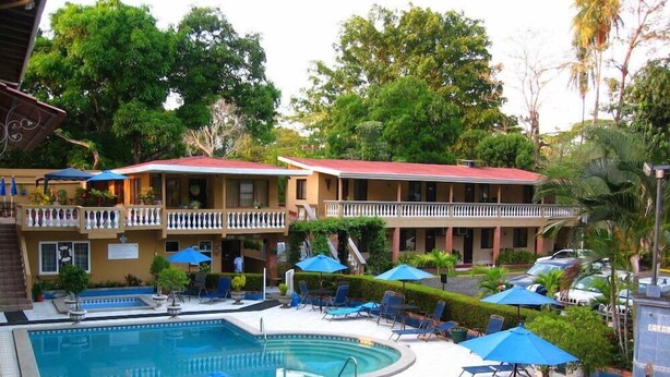 Um hotel com piscina, espreguiçadeiras e guarda-sóis.