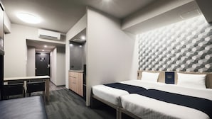 Quarto de hotel com uma cama grande, uma mesa e uma kitchenette.