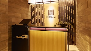 Uma mesa de recepção com um logotipo, uma planta e um painel decorativo de madeira.