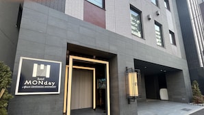 A modern hotel entrance with a sign for "MONDAY Abare AKIHABARA SOUTH EAST".
