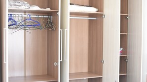 Guarda-roupa de madeira com várias prateleiras e espaço para pendurar, incluindo uma barra de metal para roupas.