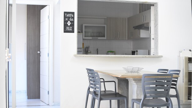Cozinha moderna com mesa de madeira e quatro cadeiras, micro-ondas embutido e armários.