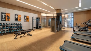 Uma academia com esteiras, máquinas de musculação e halteres.
