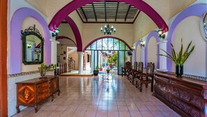 Um hall amplo com tetos altos, portas em arco e um lustre central.
