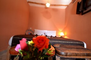 Quarto com cama, mesa de cabeceira e uma mesa com um vaso de flores.