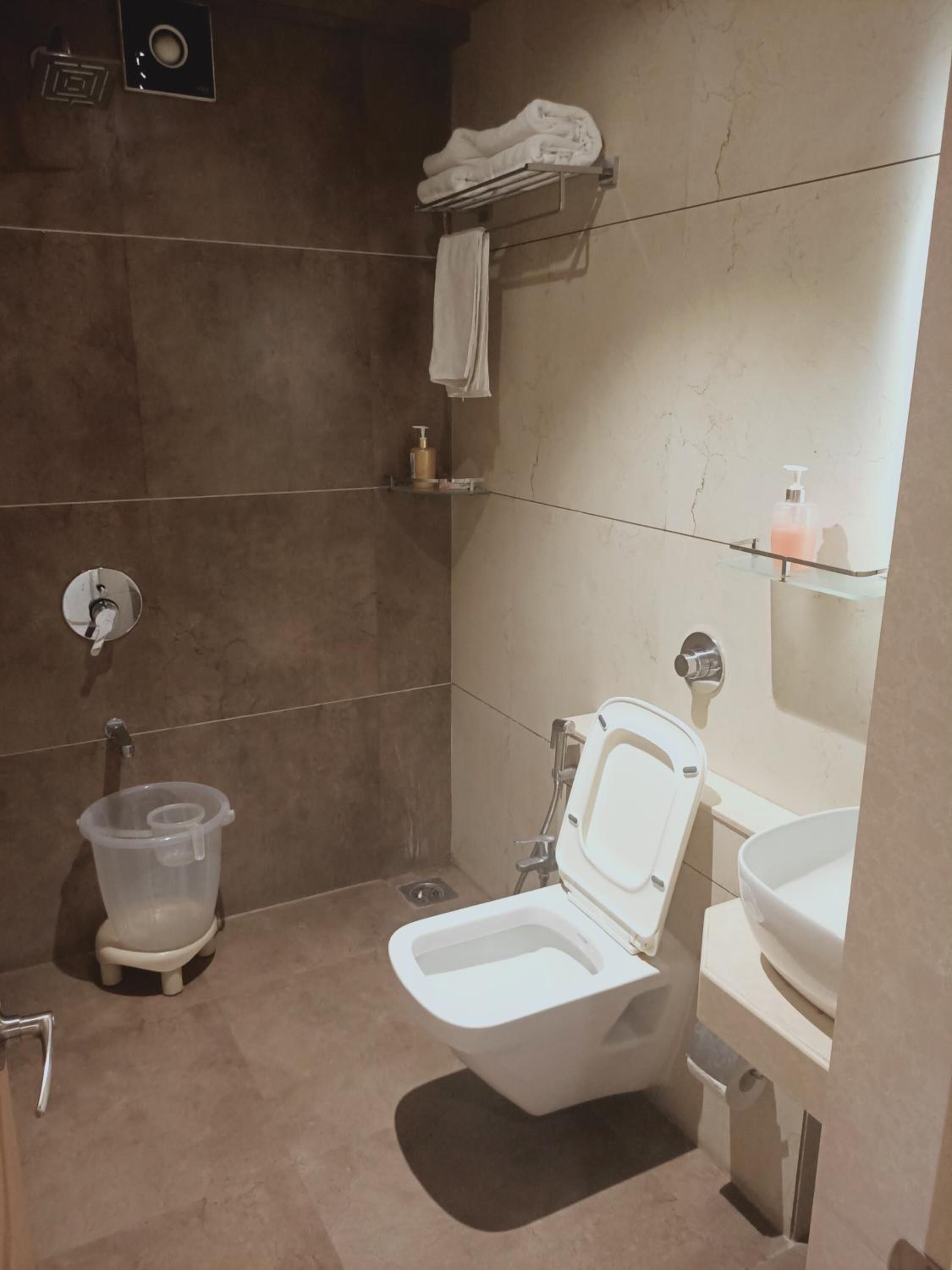 Casa de banho compacta com sanita, lavatório e chuveiro.