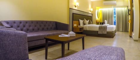 Quarto de hotel com sofá, cama, uma mesinha e um espelho.