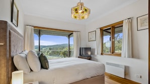 Quarto com uma cama grande, televisão e vista para o exterior.