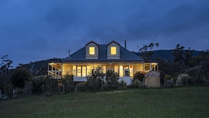 Uma casa de dois andares com uma varanda frontal notável e uma chaminé.