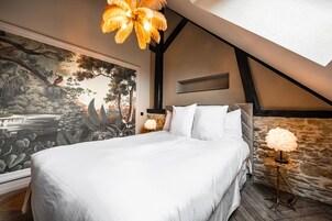 Quarto com uma cama grande, um mural de um pássaro em um galho e uma parede de pedra.