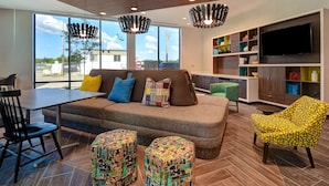 Uma sala de estar moderna com sofá, pufes, mesa de jantar e televisão.