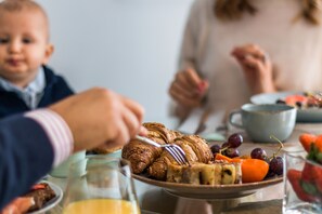Disposição de café da manhã com croissants, uvas e fatias de laranja em um prato.