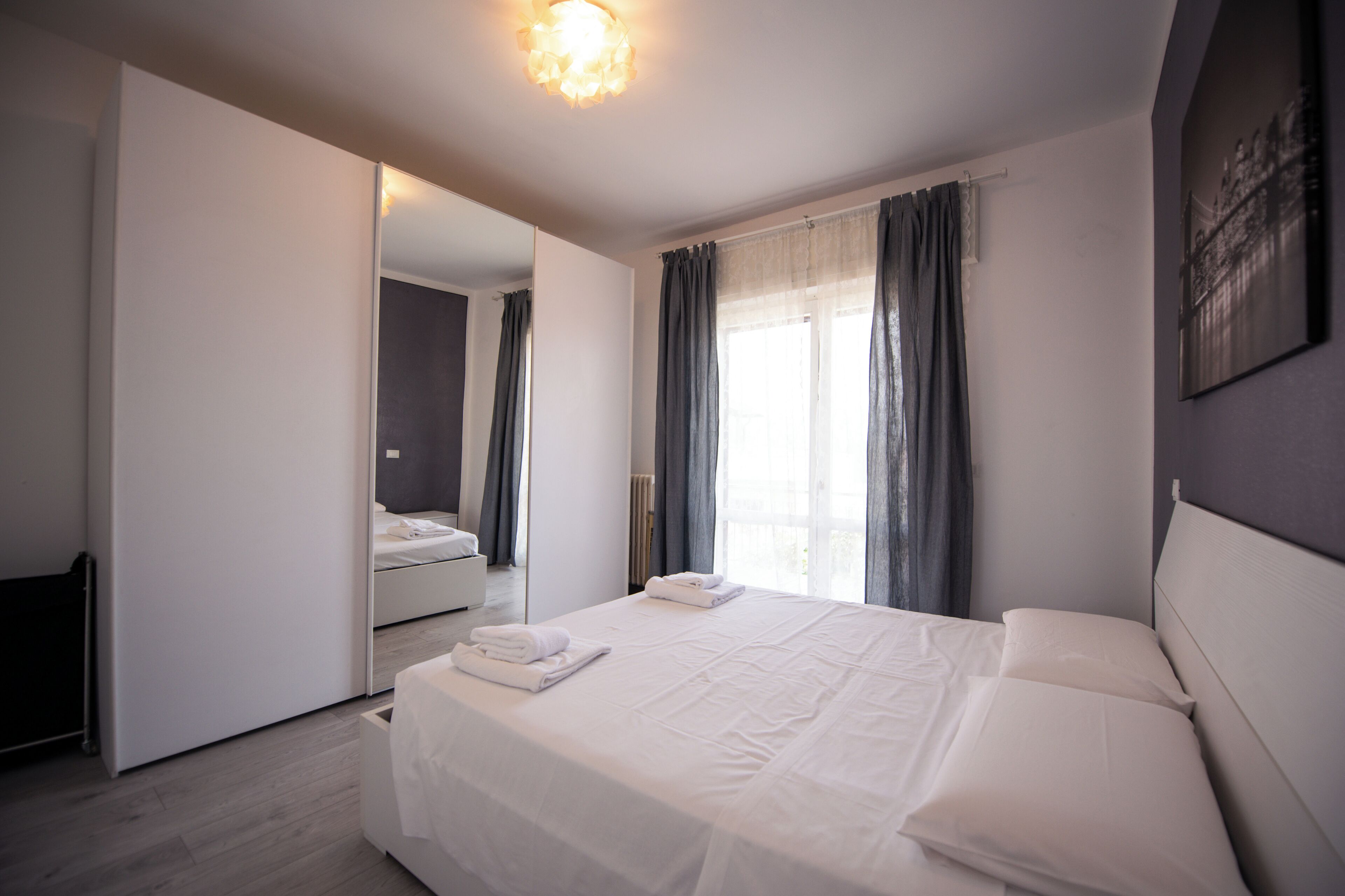 Quarto de hotel moderno com uma cama grande, um closet espaçoso e vista da cidade pela janela.