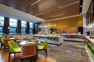Uma sala de jantar moderna com buffet central, iluminação clara e grandes janelas.