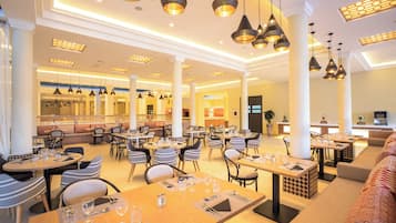 Um restaurante espaçoso com diversas áreas de refeição, incluindo um bar e um espaço com sofás e mesas.