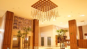 Um hall moderno com painéis de madeira, balcão de recepção de vidro e luminárias pendentes.