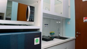 Uma cozinha com micro-ondas, pia e geladeira.