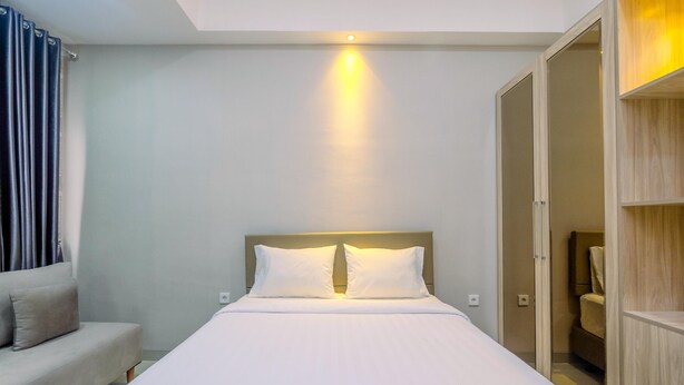 Quarto de hotel bem arrumado com uma cama, mesa de cabeceira, guarda-roupa e janela com cortinas.