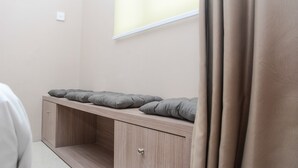 Um quarto em tons neutros, com um banco embutido e uma janela com persiana branca.