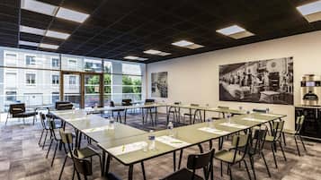 Sala de conferência com mesas de vidro, cadeiras e grandes janelas.
