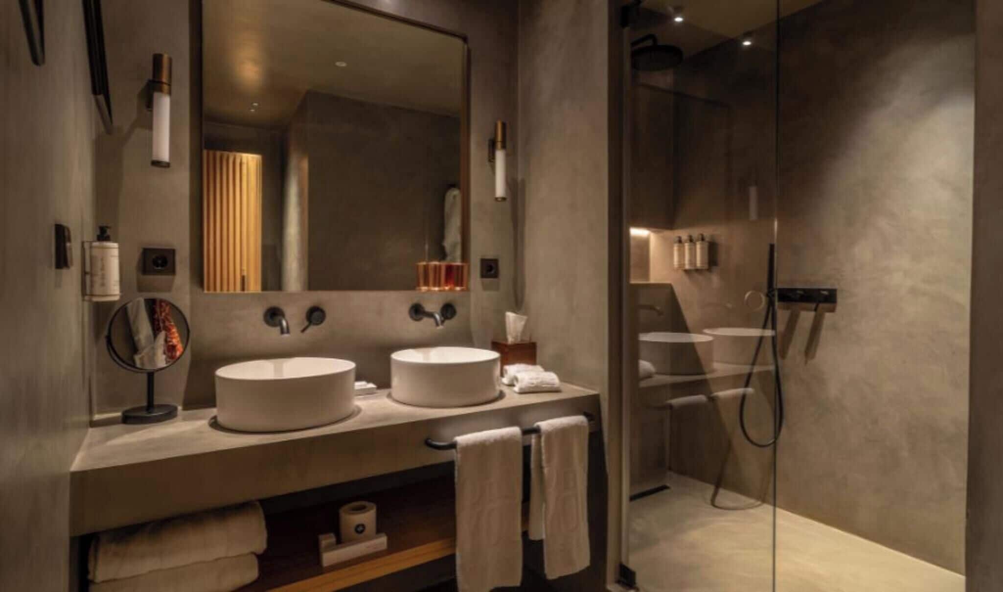 Uma casa de banho moderna com duas pias, um espelho grande e cabine de duche em vidro.