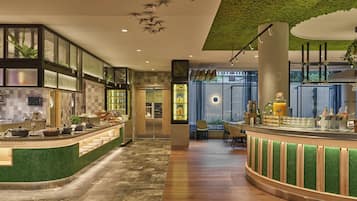 Um restaurante moderno com balcão curvo, área de bar com azulejos verdes e teto com luminárias pendentes.