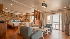 Ampla sala de estar com piso de madeira, um sofá, uma mesa de centro e vista para o mar através de grandes janelas.