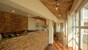 Uma área de recepção com um design exclusivo na parede, em tecido trançado, um balcão de madeira e um teto com padrão natural.