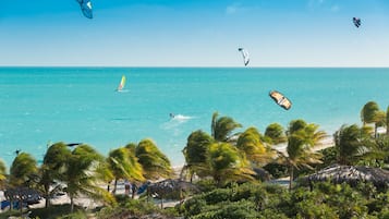 Na praia, areia branca, espreguiçadeiras, guarda-sóis