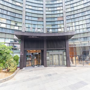 Uma entrada de hotel moderna com uma porta giratória, grandes janelas de vidro e uma placa com a inscrição "JI HOTEL".