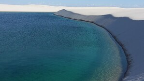 Paisagem costeira com uma praia arenosa e mar azul cristalino.