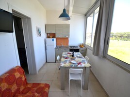Uma cozinha compacta com mesa, cadeiras e geladeira.