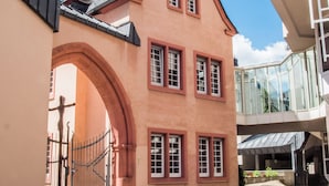 Um edifício com fachada vermelha e telhado preto, apresentando uma grande entrada em arco e várias janelas.