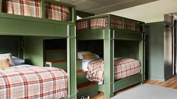 Quarto com beliche, paredes verdes e roupa de cama xadrez.