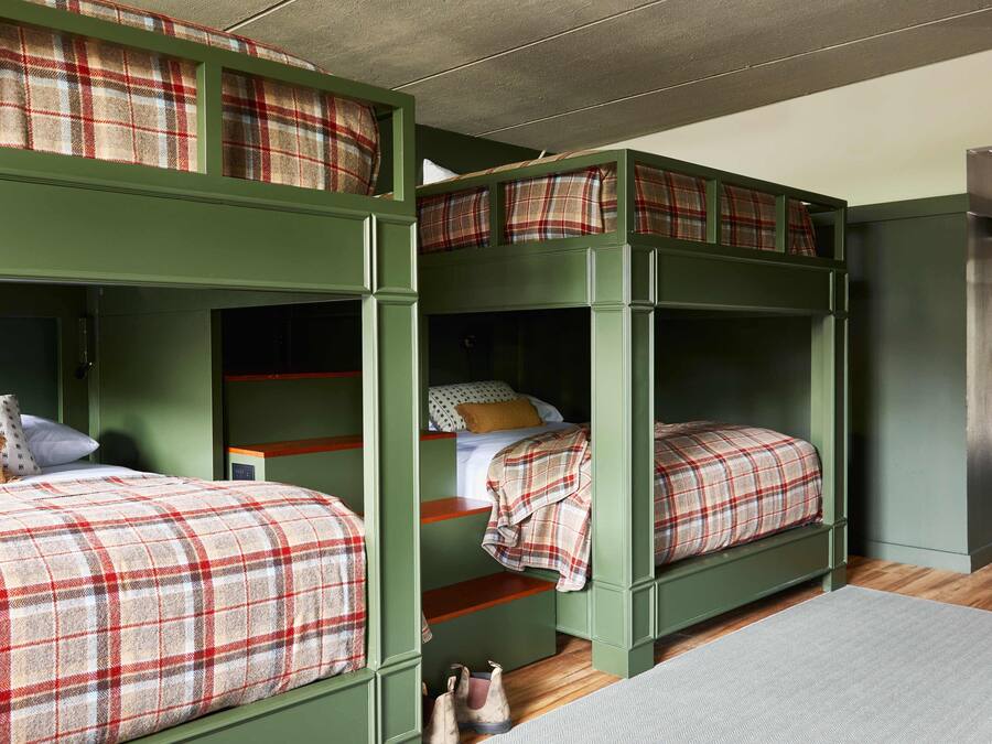 Quarto com beliche, paredes verdes e roupa de cama xadrez.