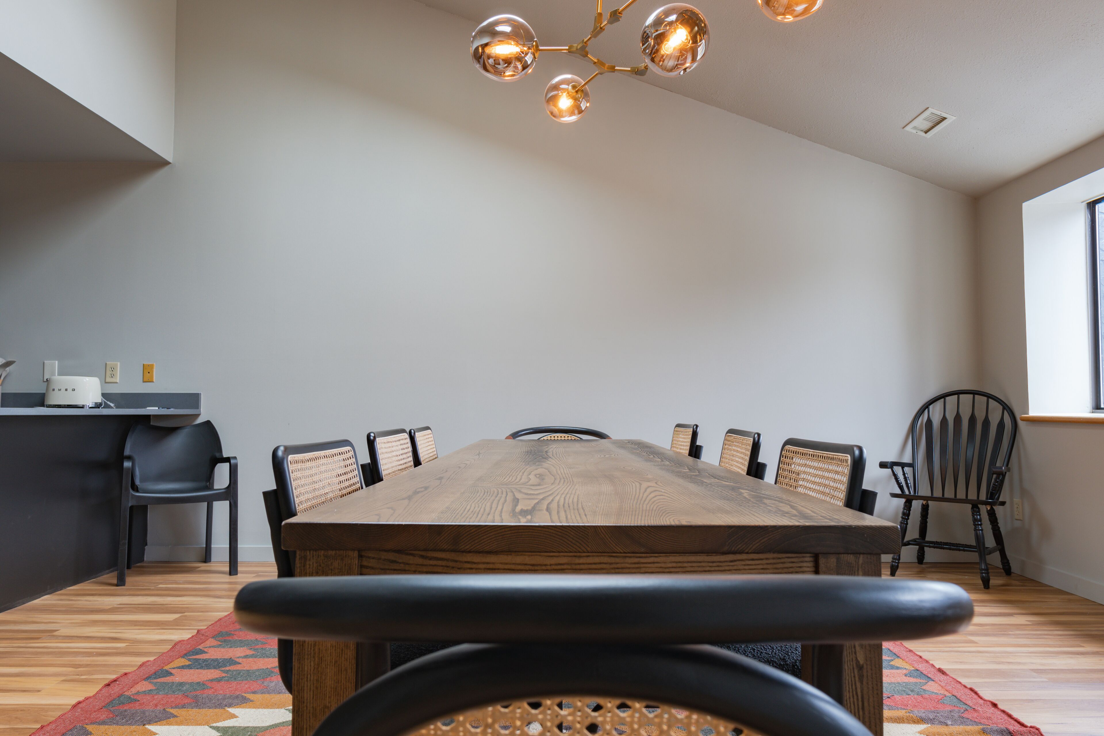 Uma zona de refeições moderna com uma mesa de madeira, cadeiras e um candelabro.