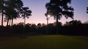 Um parque ao anoitecer, com árvores e uma mesa para piquenique.