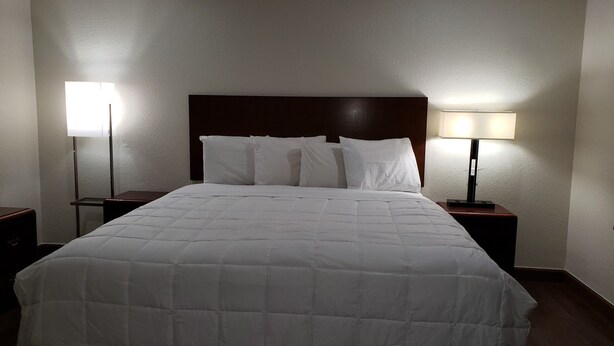 Quarto de hotel com uma cama grande, duas mesas de cabeceira e duas luminárias fixadas na parede.