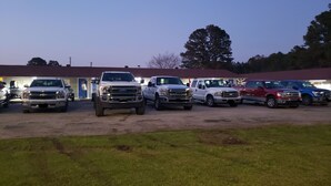 Um estacionamento com várias camionetas estacionadas em frente a um edifício com telhado vermelho.
