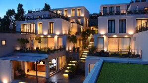 Um hotel de vários andares com design moderno, apresentando varandas, uma área de recepção e interior bem iluminado.