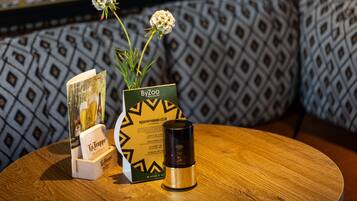 Uma mesa de madeira com um cardápio, um vaso com flores e uma vela.