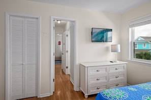 Quarto com cama, cômoda, quadro e janela.