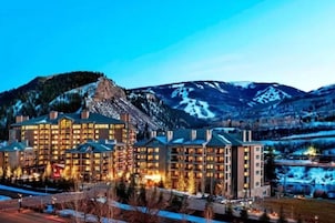 Um hotel de vários andares com um pátio central, rodeado por montanhas cobertas de neve.