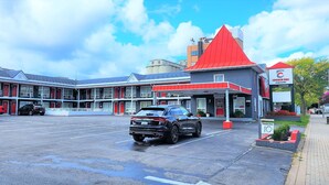 Um motel com telhado vermelho, estacionamento e uma placa indicando 'Choice Inn'.