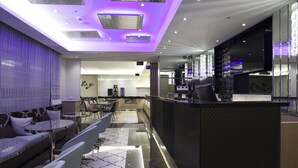 Um hall de hotel moderno com uma recepção, área de estar e um bar.