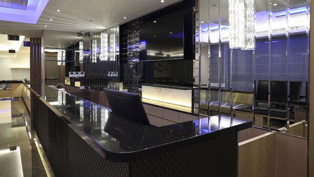 Um hall de hotel moderno com balcão de recepção, área de estar e um espelho grande que reflete o interior.