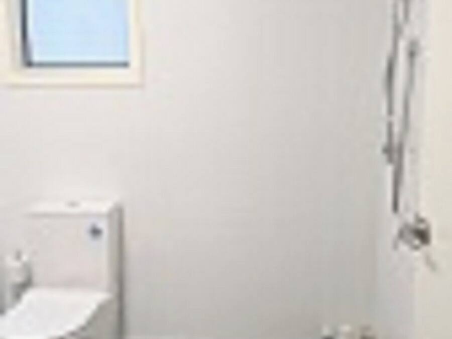 Um banheiro pequeno e simples, com vaso sanitário, janela e chuveiro.