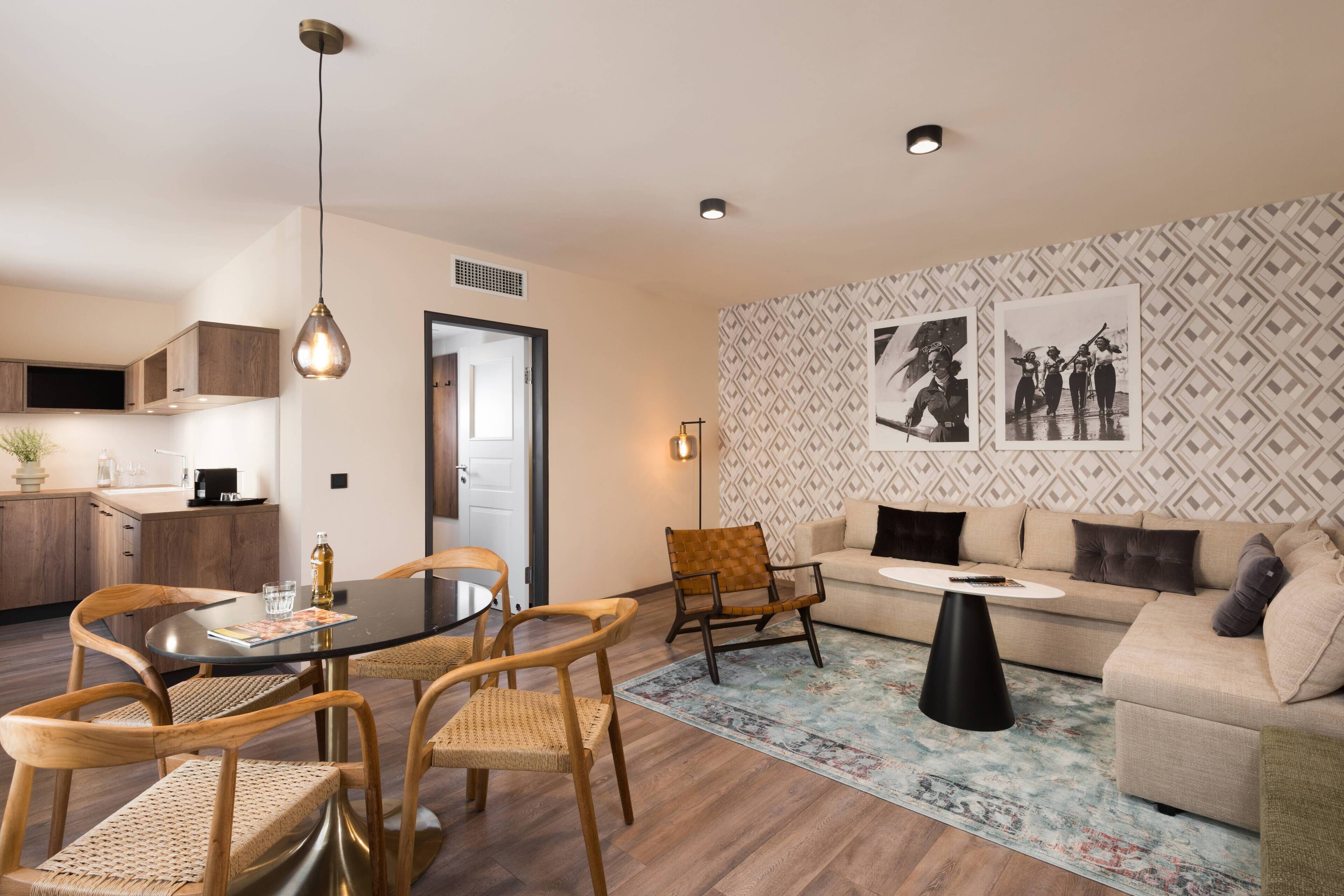 Uma sala de estar moderna com área de jantar, apresentando uma mesa redonda, cadeiras de madeira, um sofá e uma parede com padrão.