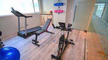 Uma academia com esteira, bicicleta ergométrica e bola de exercícios.