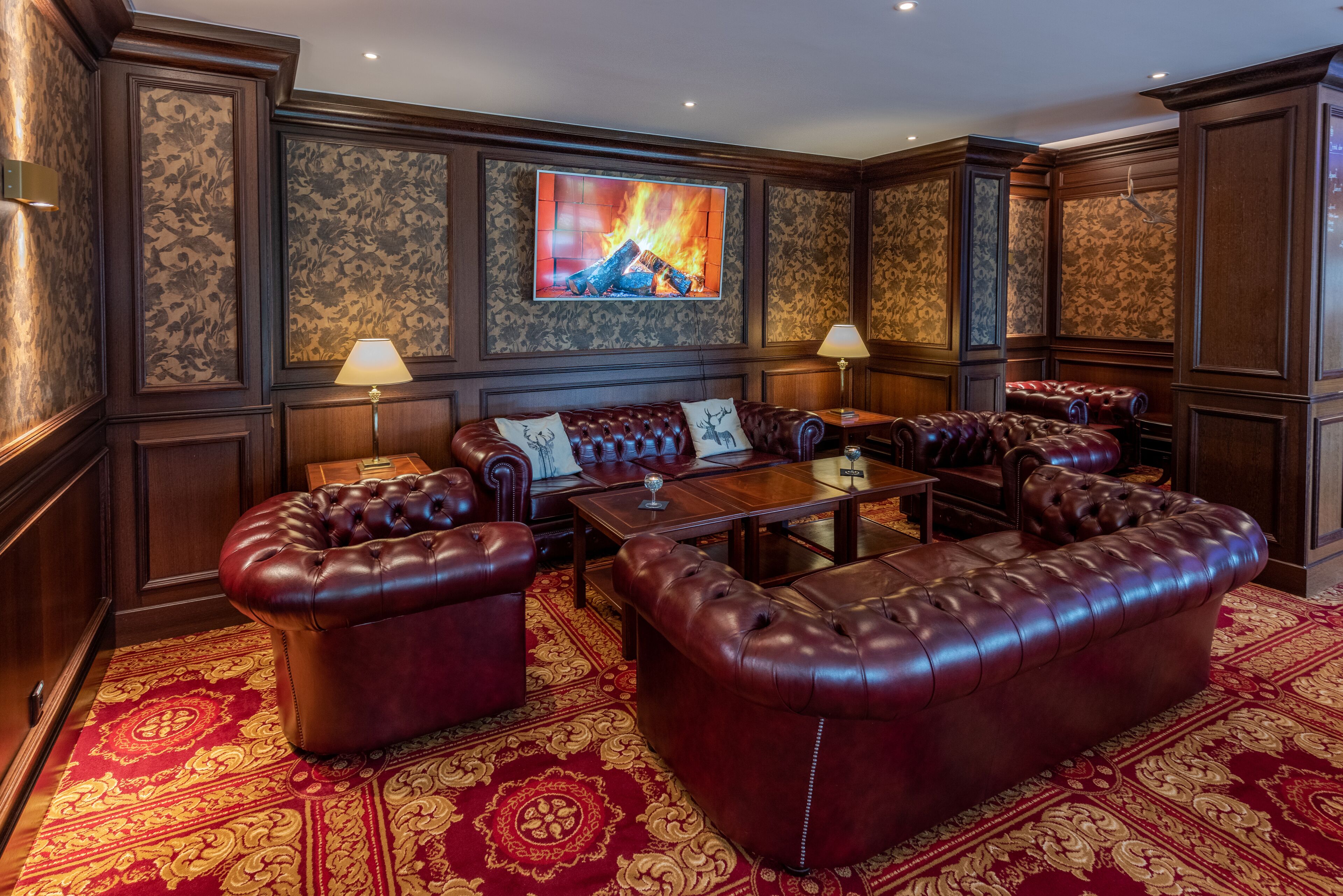 Quarto luxuoso com um amplo sofá de couro, uma mesa de centro de madeira e uma lareira com fogo.